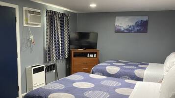 Quarto de hotel com duas camas, uma televisão, um quadro e uma janela com cortinas.