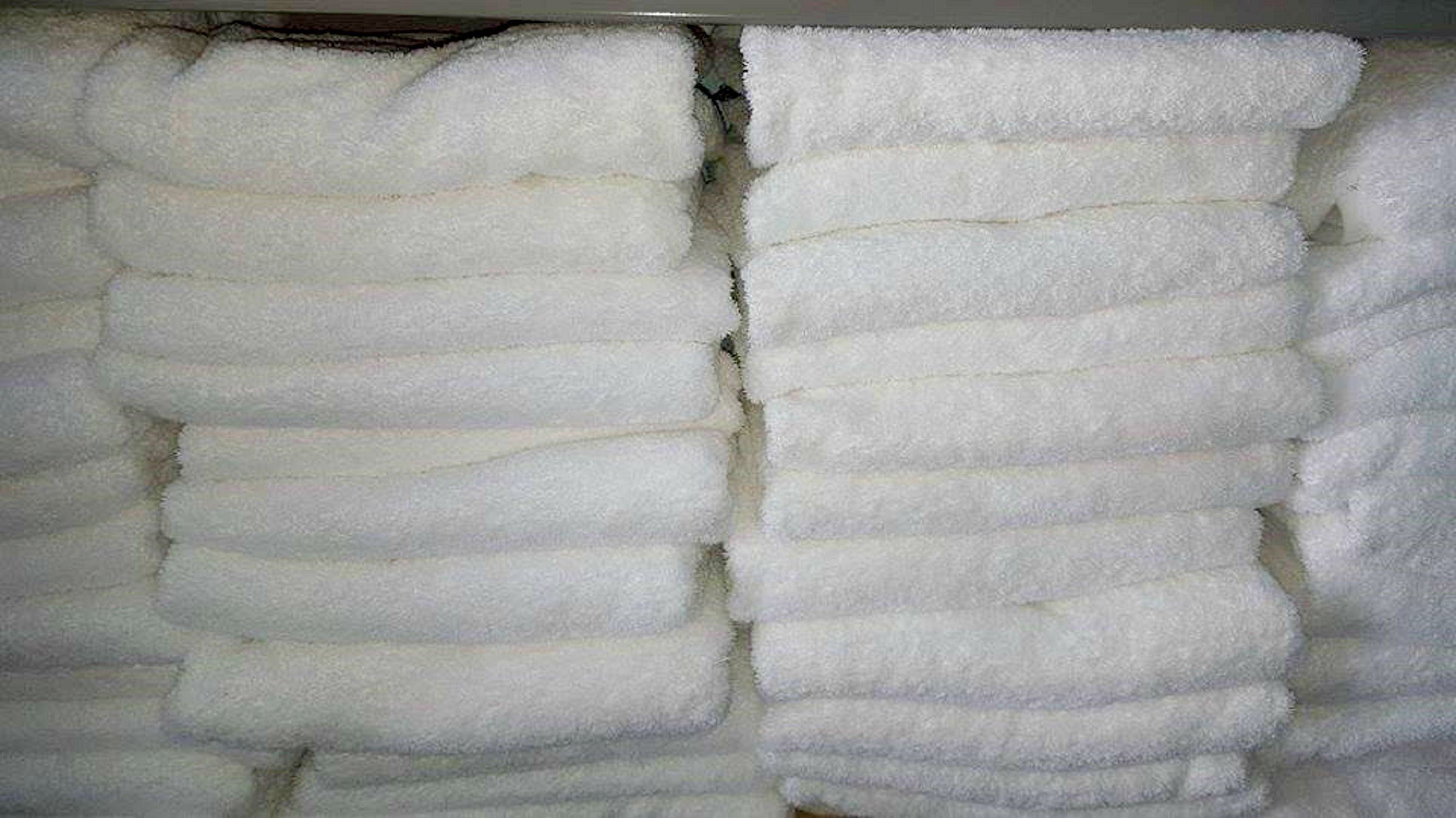 Toalhas brancas empilhadas de forma organizada em uma casa de banho.