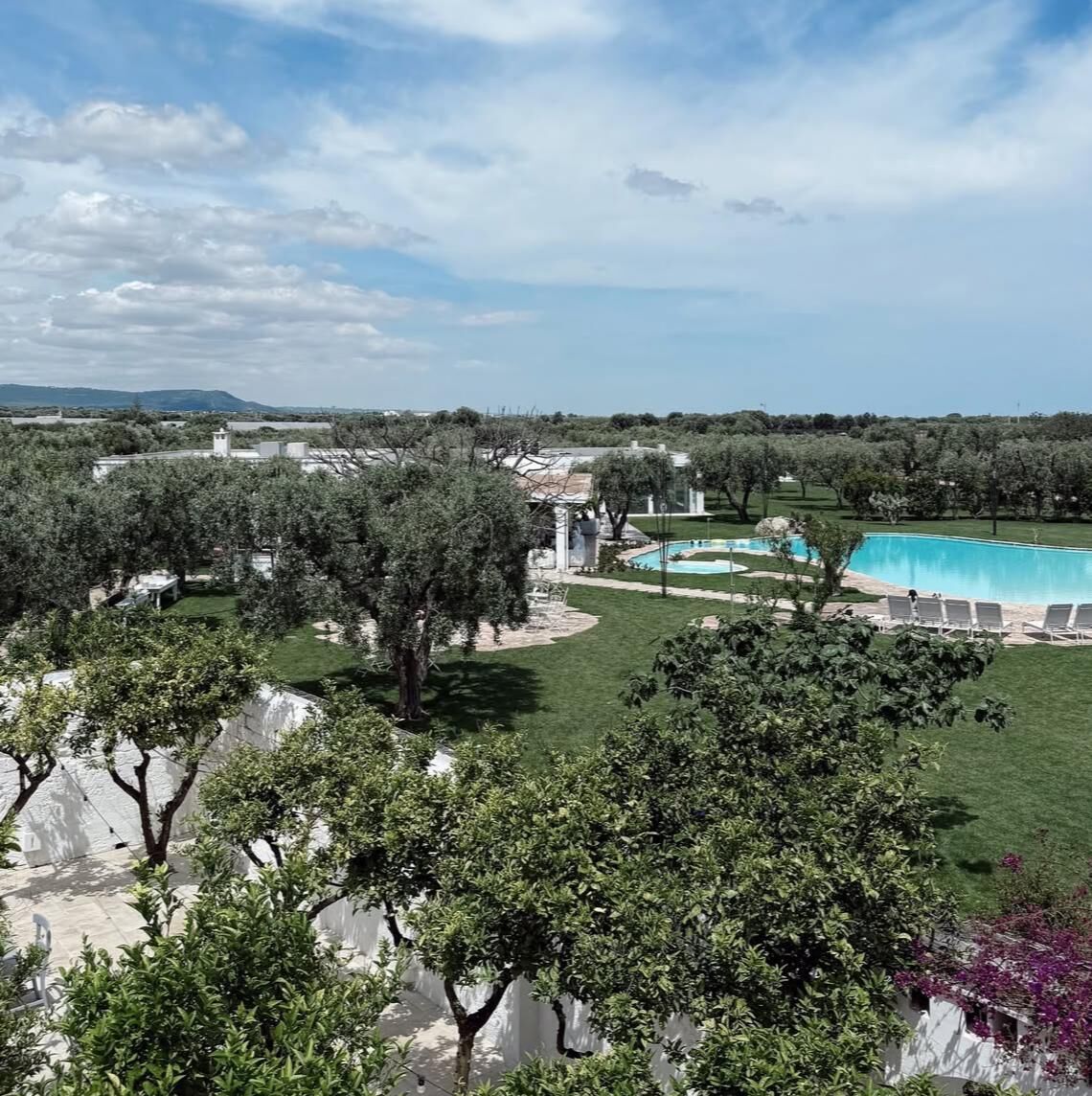Um resort com piscina, gramados verdes e árvores.