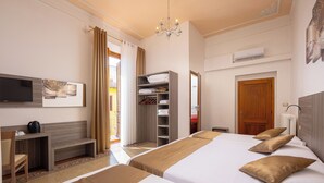 Quarto de hotel com duas camas, televisão, escrivaninha e guarda-roupa.
