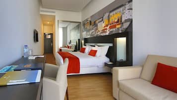 Quarto de hotel com uma cama, uma escrivaninha, uma cadeira, um sofá e um espelho grande.