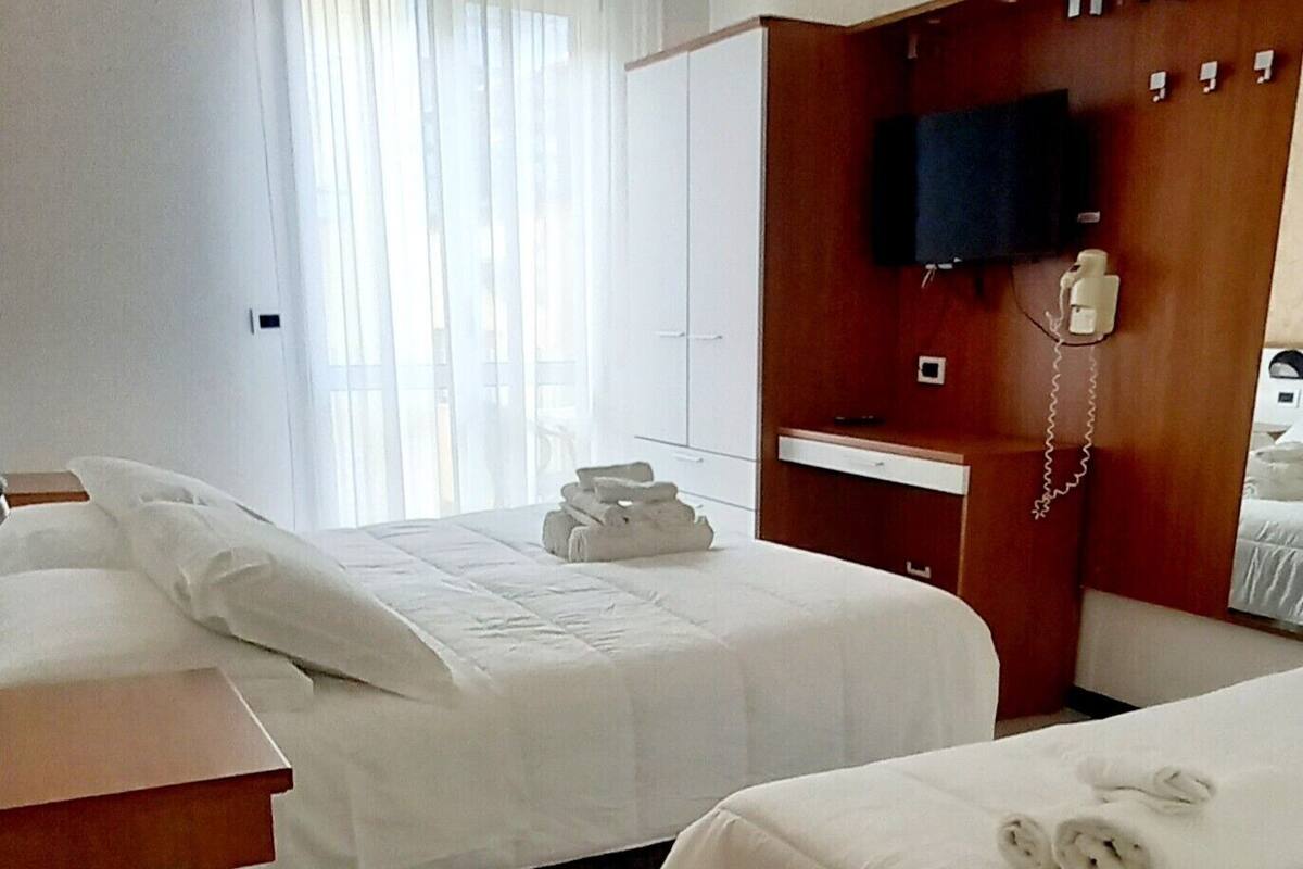 Quarto de hotel com duas camas, televisão, telefone e escrivaninha.
