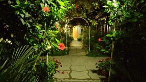 Um caminho de pedra serpenteia por um jardim exuberante com um arco de madeira.