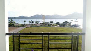 Vista de uma marina com barcos, uma área gramada e uma cordilheira ao fundo.