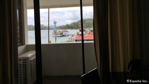 Um quarto com vista para um lago, um edifício com telhado vermelho e um poste de eletricidade.