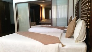 Quarto de hotel com duas camas, um espelho grande e uma porta de vidro deslizante que dá para um banheiro.