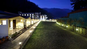 Um hotel com vários edifícios, um caminho bem iluminado e uma área gramada.