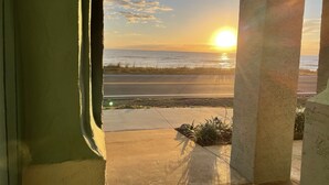 Vista do oceano ao pôr do sol através de uma janela com estrutura de concreto.