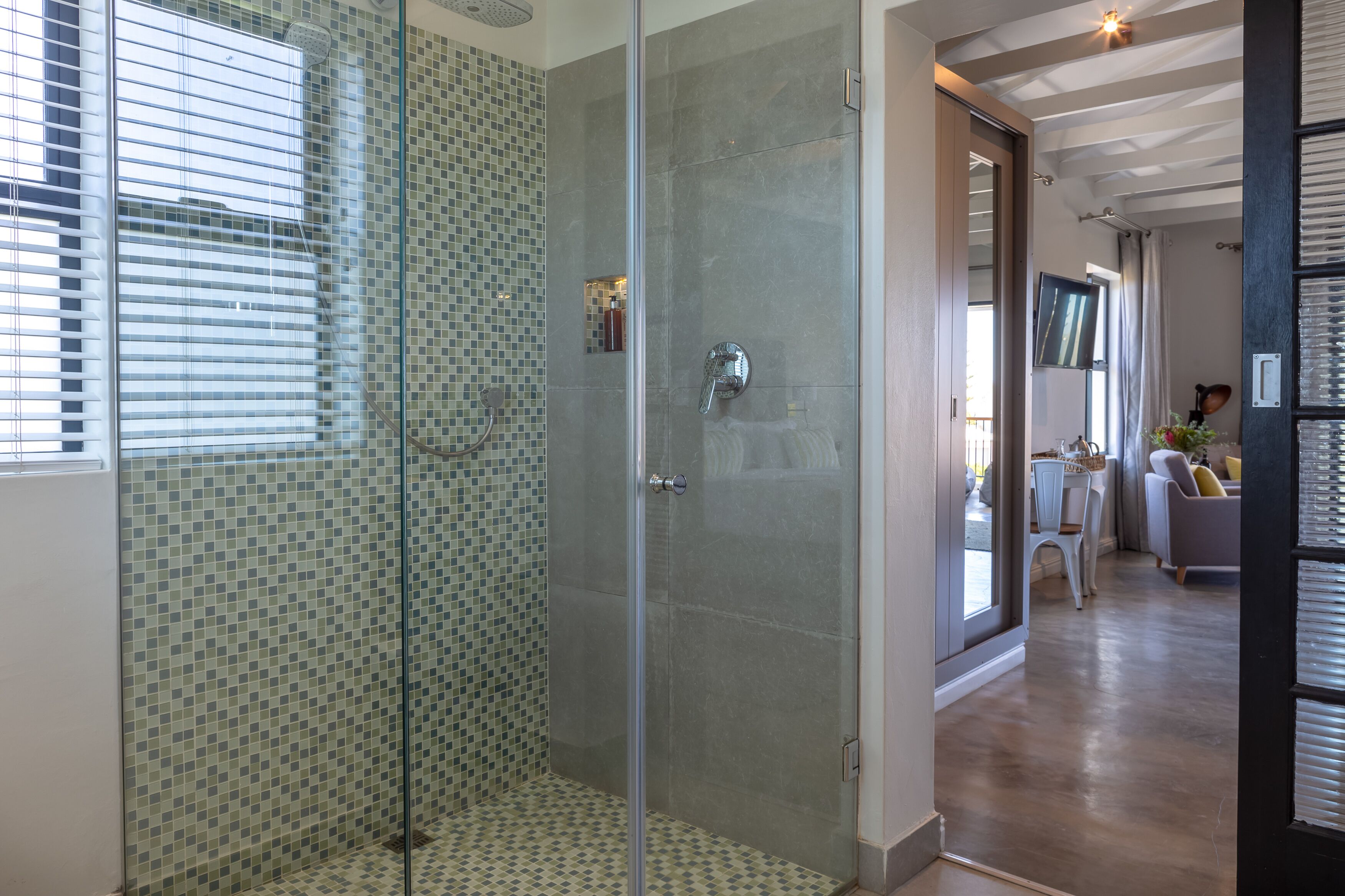 Um banheiro moderno com box de vidro, paredes revestidas com azulejos e vaso sanitário à mostra.