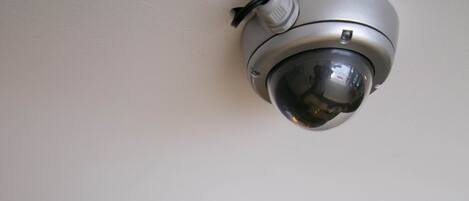 Câmera de segurança fixada na parede com um letreiro de hotel abaixo.