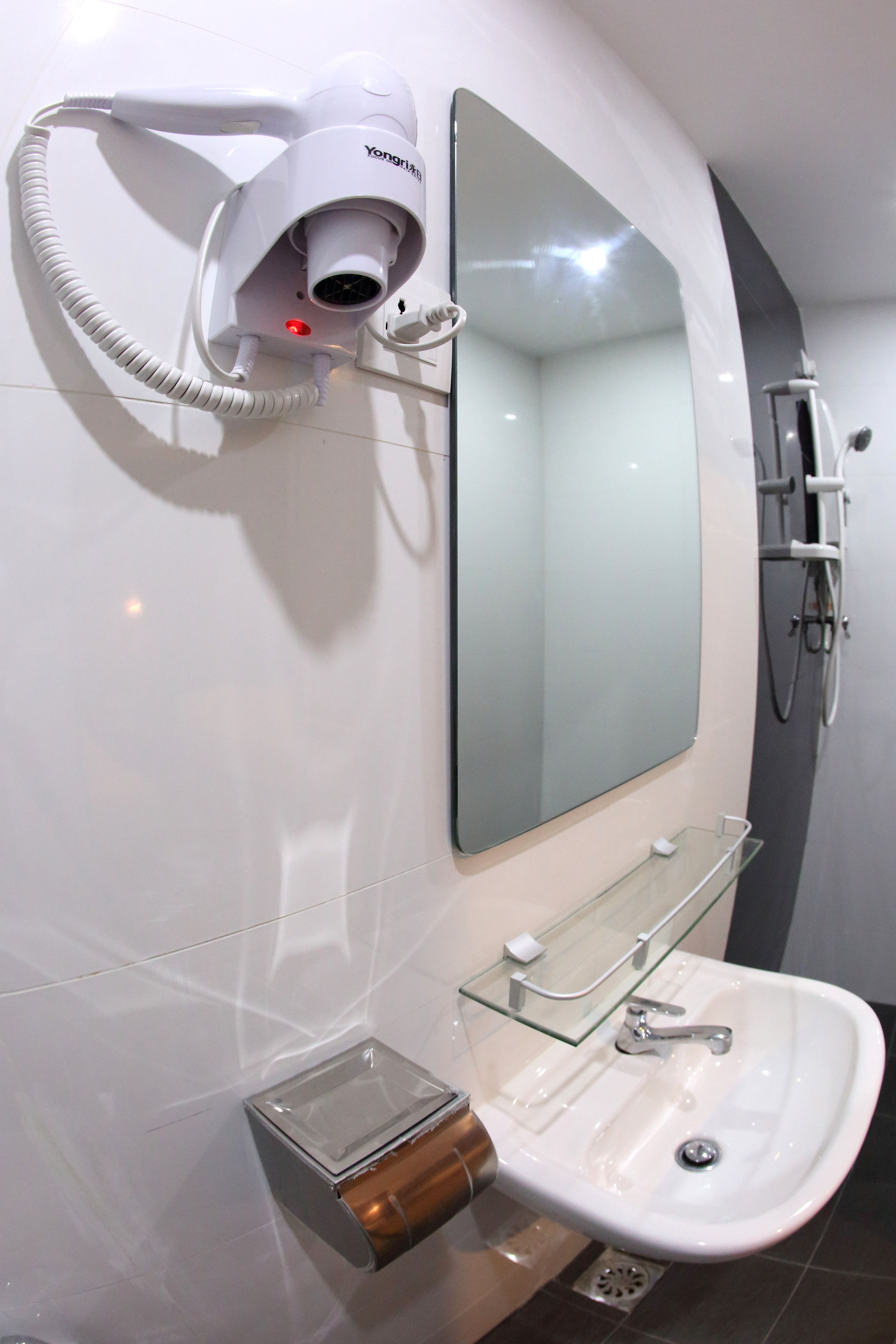 Uma casa de banho moderna com secador de cabelo, um espelho grande, uma prateleira de vidro e uma pia.