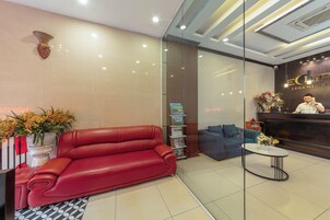 Um lobby de hotel moderno com um sofá de couro vermelho, um balcão de recepção e uma mesa de centro pequena.