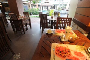 Uma mesa de jantar de madeira com cadeiras, uma cesta de morangos e uma chaleira.