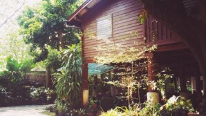 Uma casa de madeira com varanda, cercada por muita vegetação.