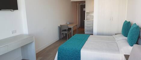 Quarto de hotel moderno com uma cama, uma escrivaninha, uma cadeira e uma televisão.