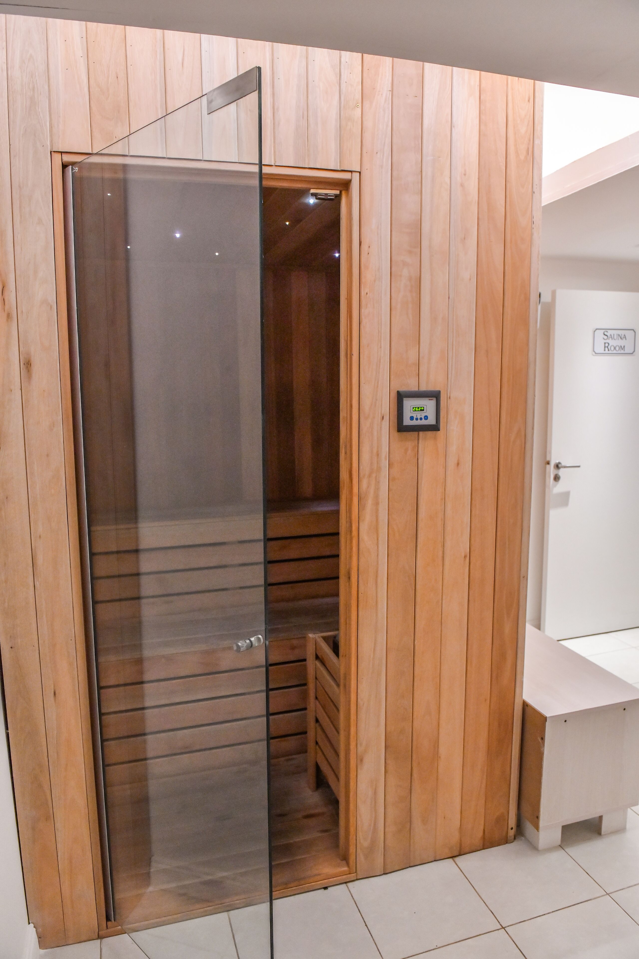 Sala de sauna com paredes de madeira e porta de vidro.