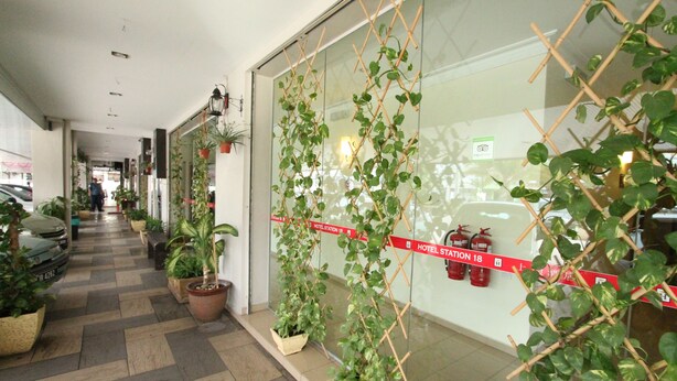 Corredor de hotel com plantas em vasos, um extintor de incêndio e fita de segurança vermelha.