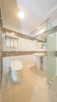 Uma casa de banho moderna com sanita, lavatório e cabine de duche em vidro.