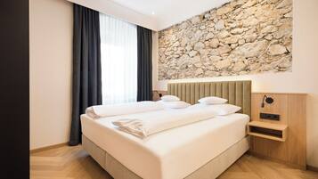 Um quarto moderno com uma cama grande, uma parede de pedra e uma cabeceira de madeira.