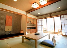 Um quarto japonês tradicional com tatames, uma mesa de madeira baixa e portas deslizantes shoji.