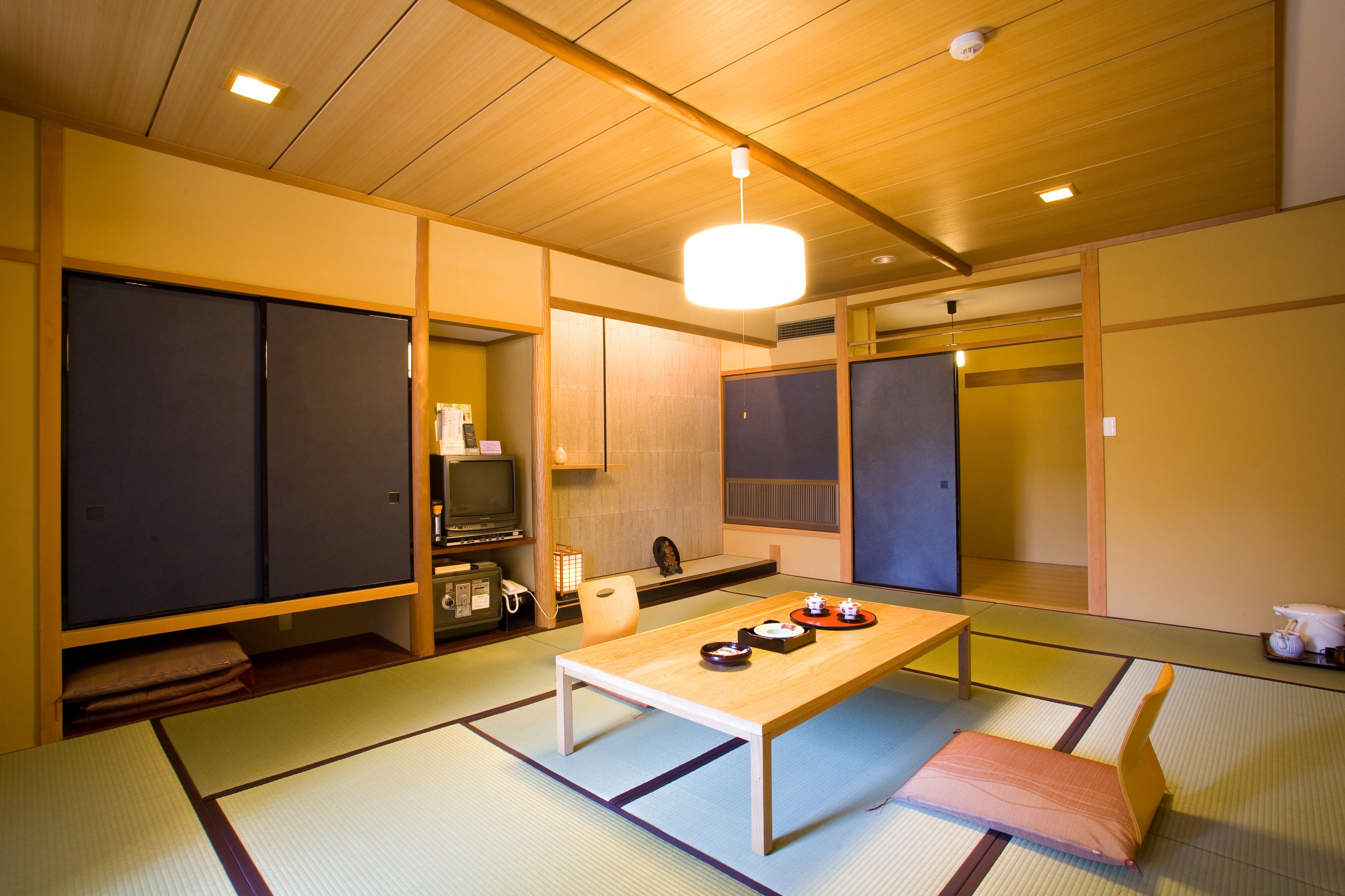 Um quarto japonês tradicional com piso de tatame, uma mesa baixa e portas deslizantes.