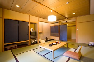 Um quarto japonês tradicional com piso de tatame, uma mesa baixa e portas deslizantes.
