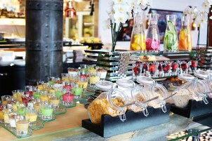 Buffet com diversas opções de comida e bebida, incluindo potes de granola e uma seleção de bebidas coloridas.