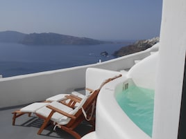 Varanda com duas poltronas de madeira e uma piscina pequena.