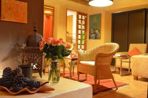 Uma sala de estar aconchegante com móveis de vime, um vaso de flores e um cesto decorativo.