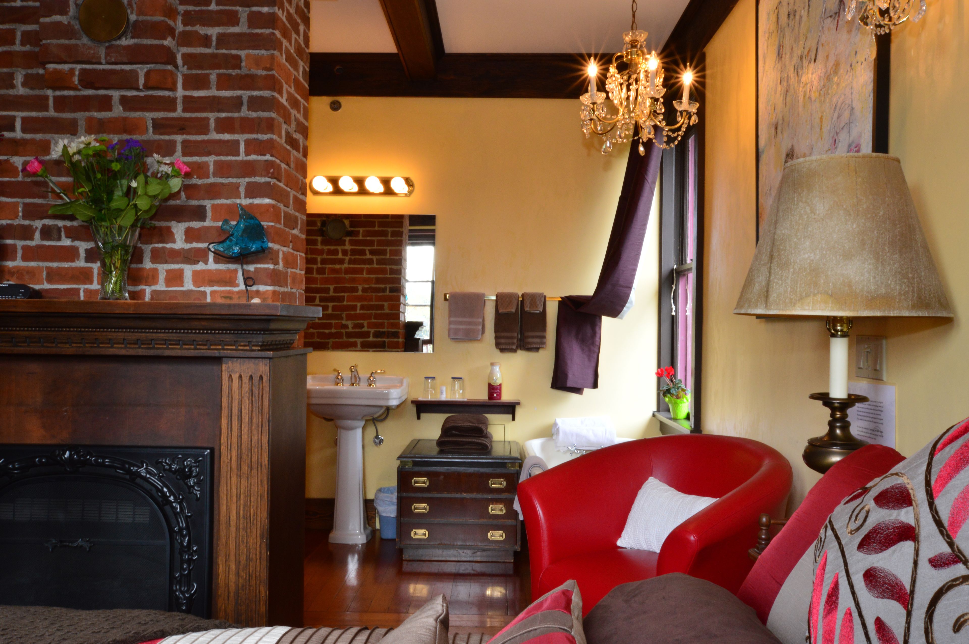 Uma sala de estar com lareira, poltrona vermelha e um candelabro.