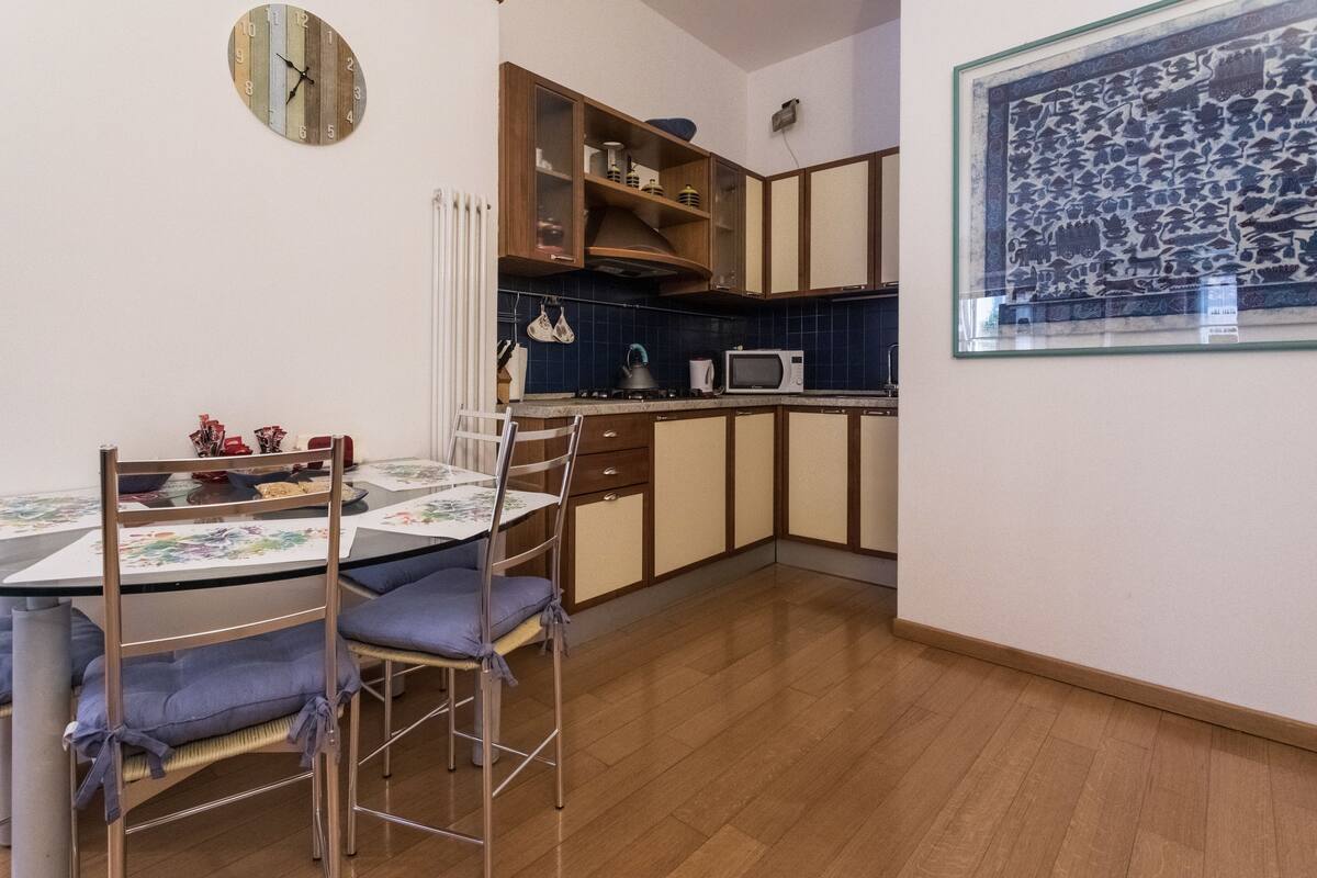 Uma cozinha compacta com armários de madeira, um micro-ondas e um relógio na parede.