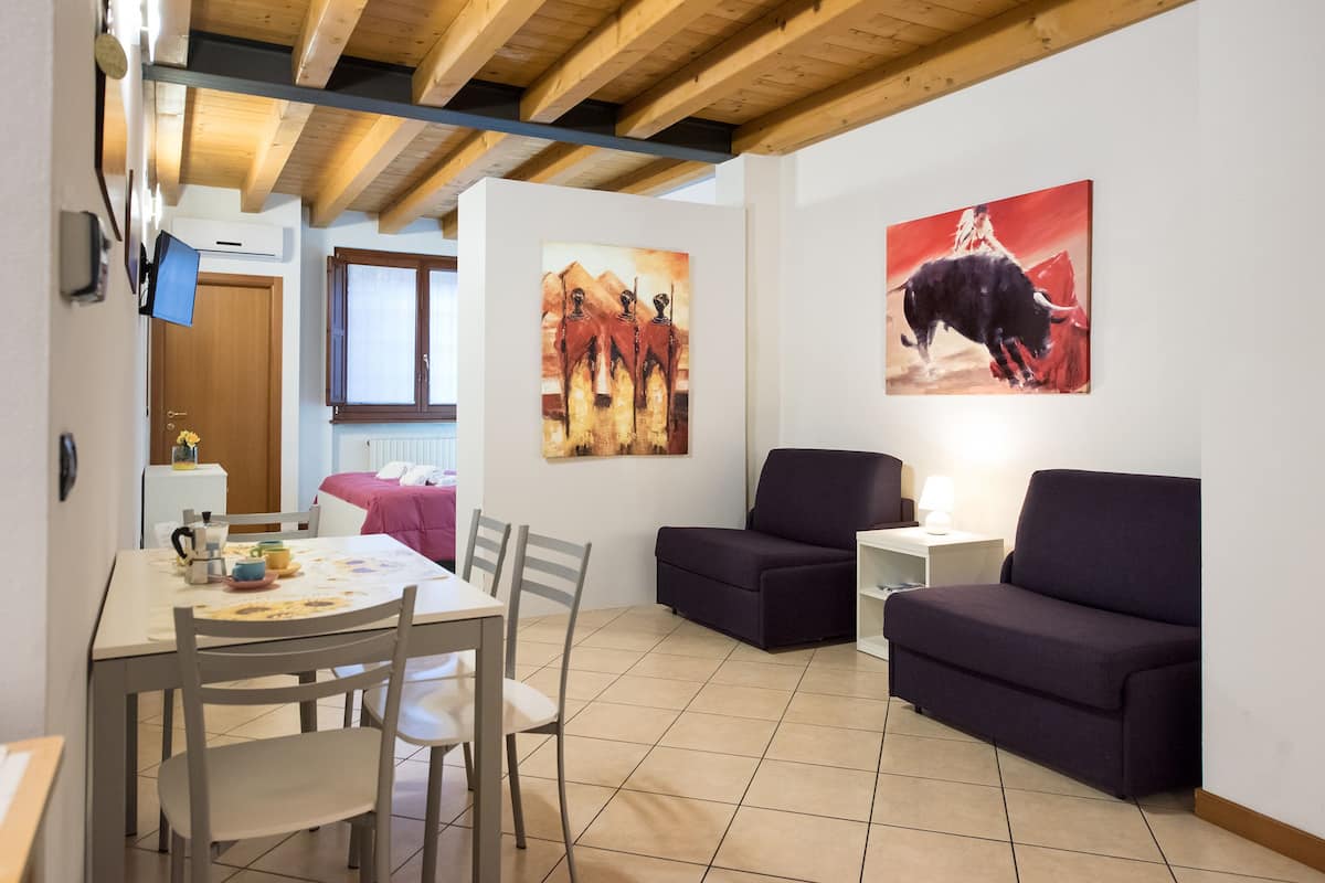 Uma sala de estar com uma mesa de jantar, dois sofás e um quadro grande de um touro.