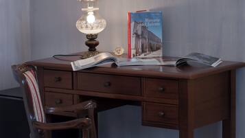 Uma mesa de madeira com uma lâmpada, um livro intitulado 'Masserie del Salento' e uma revista aberta.