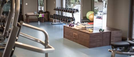Uma academia com equipamentos de ginástica, um banco e um suporte para halteres.