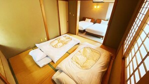 Quarto japonês tradicional com tatames, duas camas com roupa de cama branca, um painel shoji e um lampião de papel pendurado.
