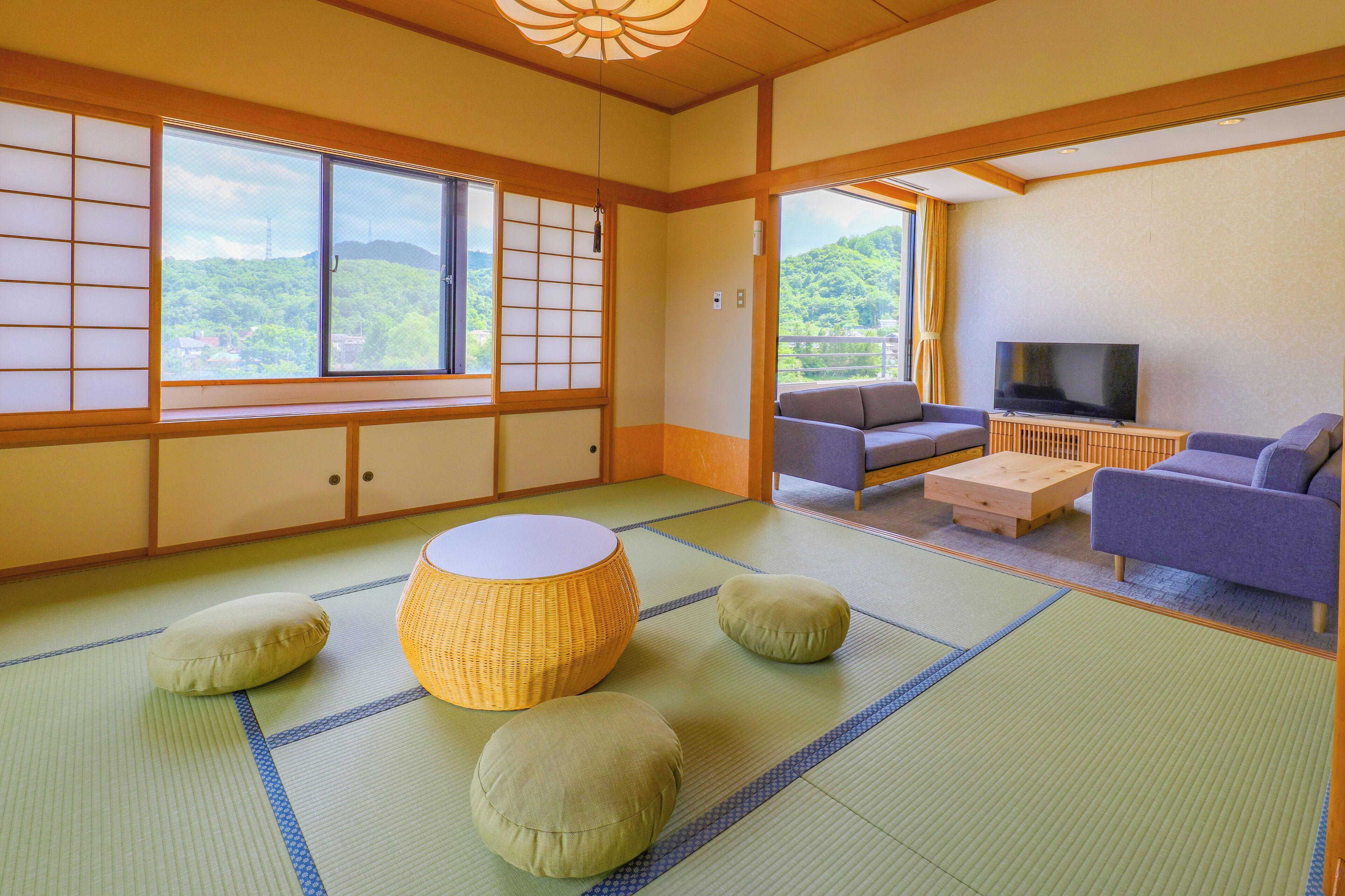 Um quarto japonês tradicional com tatames, uma mesa baixa de tatame, almofadas e uma televisão.