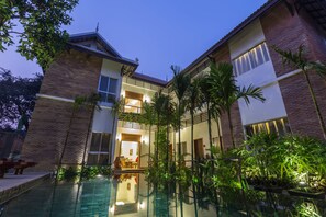 Uma casa moderna com piscina, cercada por vegetação exuberante e um interior bem iluminado.