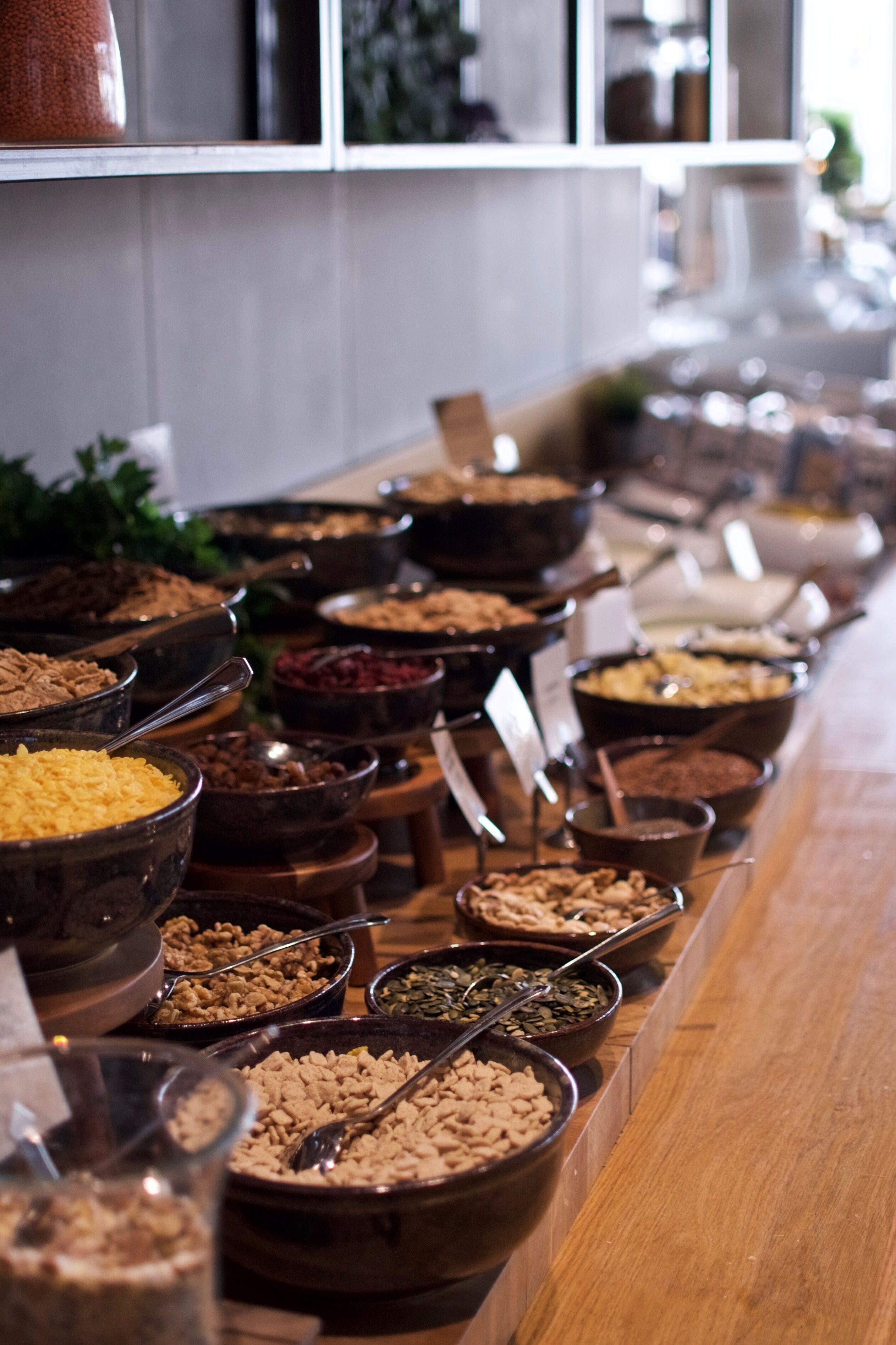 Buffet com diversos alimentos em tigelas, disposto sobre um balcão de madeira.