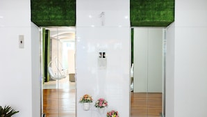 Um elevador moderno com tela digital, painel de controle e três plantas em vasos.