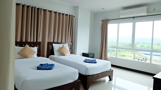 Quarto de hotel com duas camas, uma janela grande com vista e um aparelho de ar condicionado.