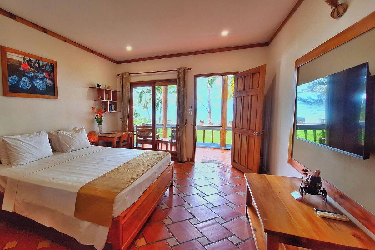 Quarto espaçoso com cama grande, televisão e varanda com vista.