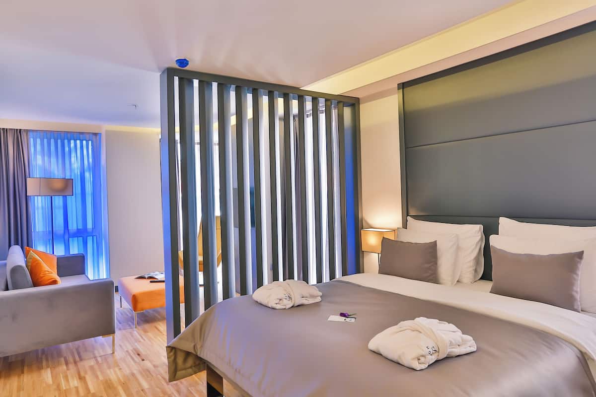 Quarto de hotel moderno com uma cama grande, um sofá e uma escrivaninha.