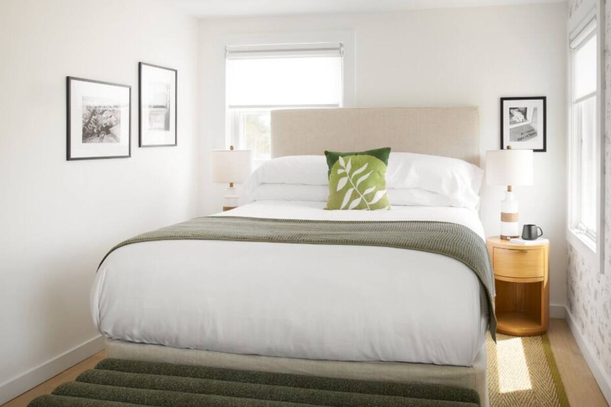 Quarto bem arrumado com cama, mesas de cabeceira e quadros nas paredes.