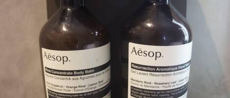 Duas embalagens de produtos Aesop em uma prateleira.