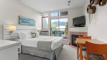 Quarto de hotel moderno com cama, mesa de cabeceira, luminária, televisão e lareira.