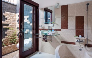 Uma casa de banho moderna com chuveiro de vidro, lavatório de vidro e uma banheira grande.