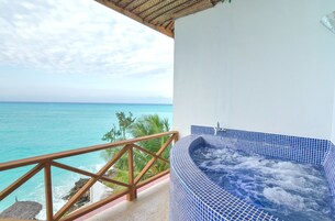 Uma varanda com vista para o oceano, guarda-corpo de madeira e uma banheira de hidromassagem com azulejos azuis.