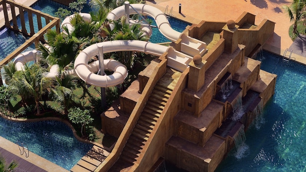 Uma área de piscina com várias cascatas aquáticas e um deck de madeira.
