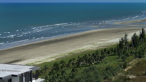 Vista costeira com praia, oceano e um edifício com telhado plano.