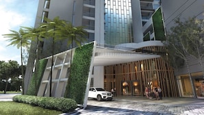 Um edifício moderno com entrada curva, um carro branco estacionado em frente e um grupo de pessoas perto da entrada.